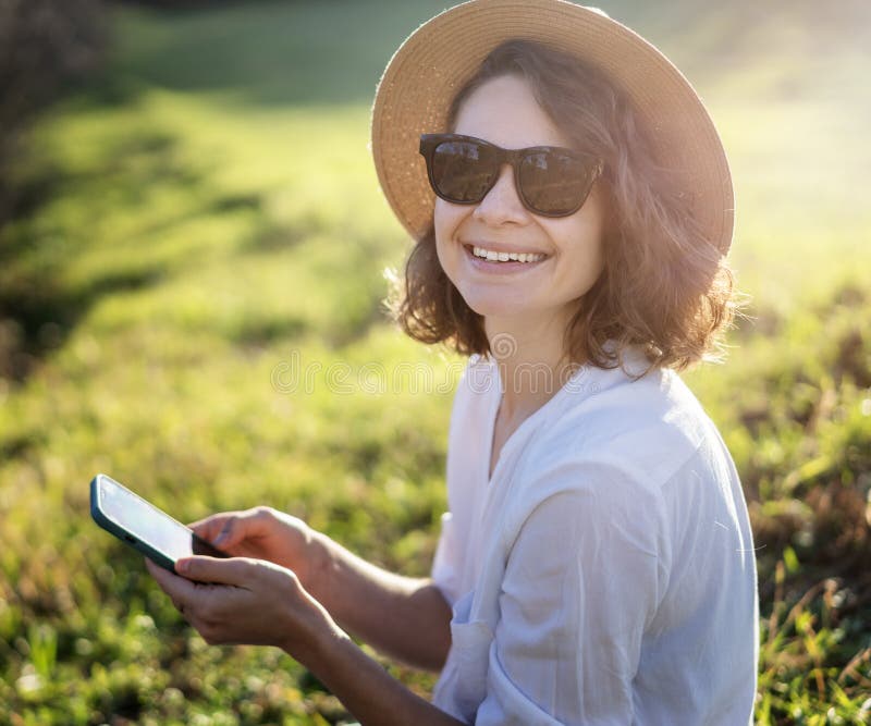 Happy Pretty Young Cheerful Woman In White Shirt And Sunglasses Using