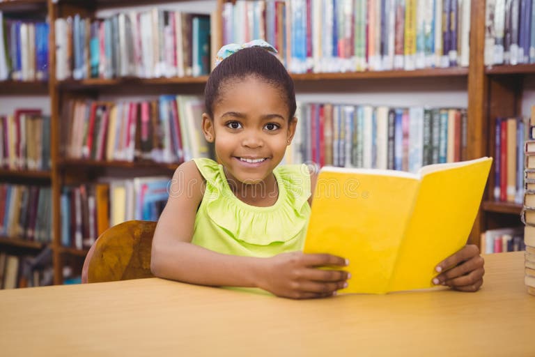 African American Boy Reading Yellow Book at Wooden Table in Library ...