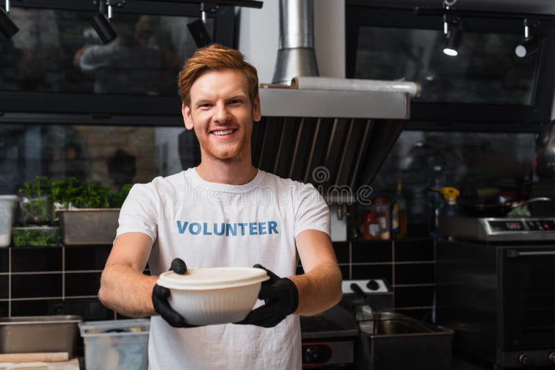 Happy Redhead Volunteer Offering Plastic Bowl Stock Photo - Image of ...