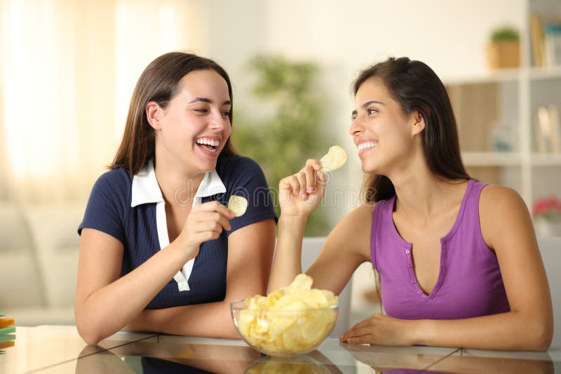 Happy Roommates Eating Potato Chips and Talking at Home Stock Image ...