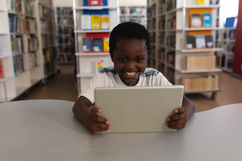 Happy Schoolboy Studying on Digital Tablet at Table in School Library ...