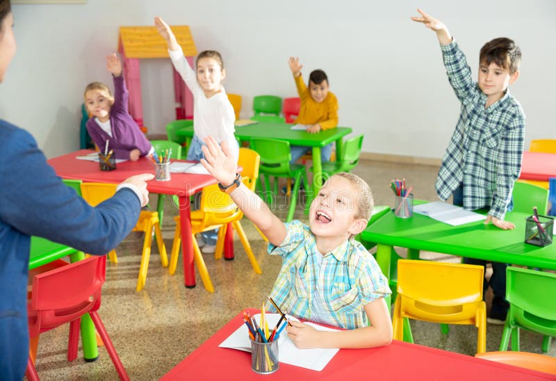 Happy Schoolchildren with Hands Raised during Lesson Stock Photo ... Happy Schoolchildren with Hands Raised during Lesson Stock Photo ...