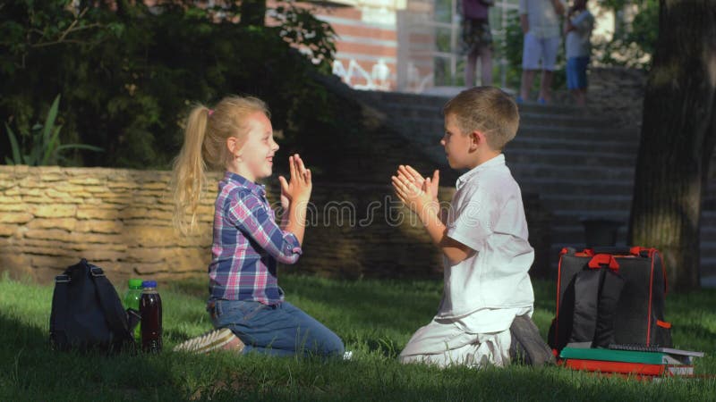 Happy Schoolchildren Playing Clapping Game Sitting in Nature after ...