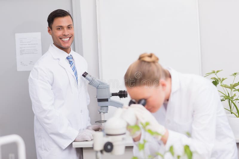 Happy Scientist Smiling at Camera Using Microscope Stock Photo - Image ...
