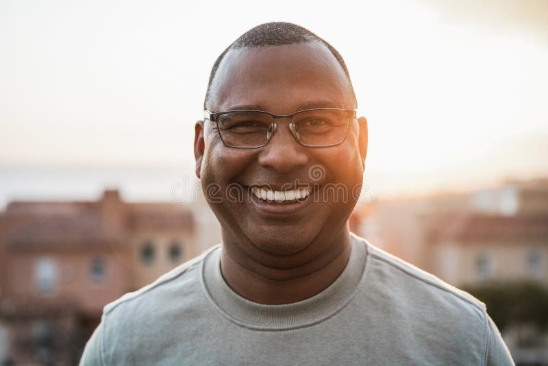 Happy Senior African Man Looking at Camera Outdoors at Sunset - Focus ...