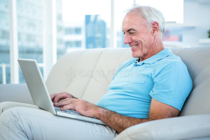 Happy Senior Man Sitting on Sofa while Using Laptop Stock Photo - Image ...