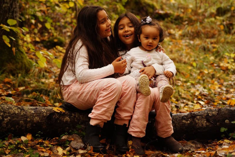 Happy Sisters Sitting on Fallen Tree in Forest Stock Image - Image of ...