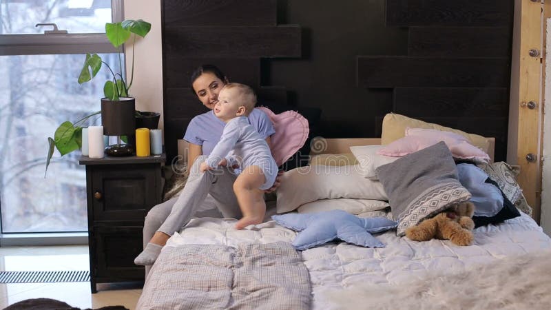 Happy Slender Mom Having Fun With A One Year Old Son In A Bright