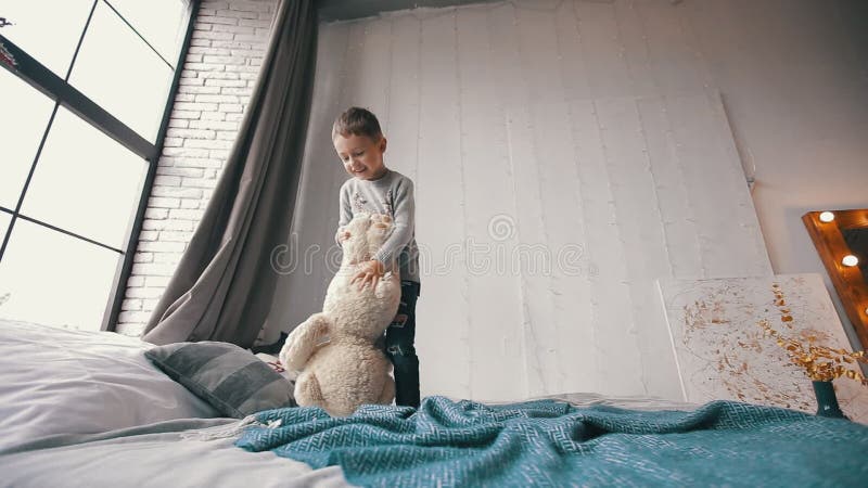Happy and Smiling Boy Jumping on a Bed and Catch a Teddy Bear Stock ...