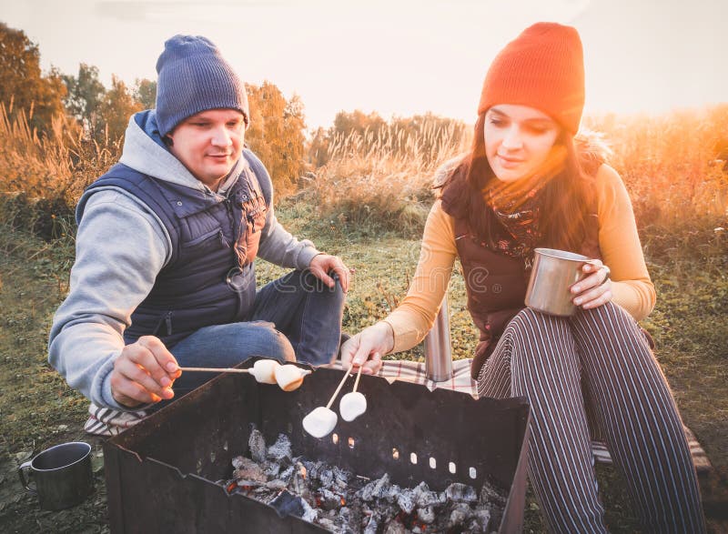 Happy Smiling Couple Roasting Marshmallows On Campfire On Nature