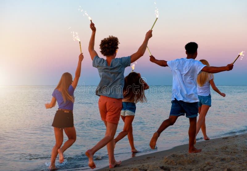 Happy Smiling Friends Running at the Beach with Sparkling Candles Stock ...
