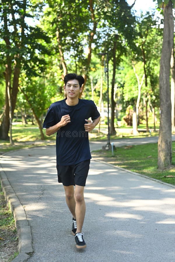 Happy Smiling Man Jogging through a Park during the Late Afternoon ...