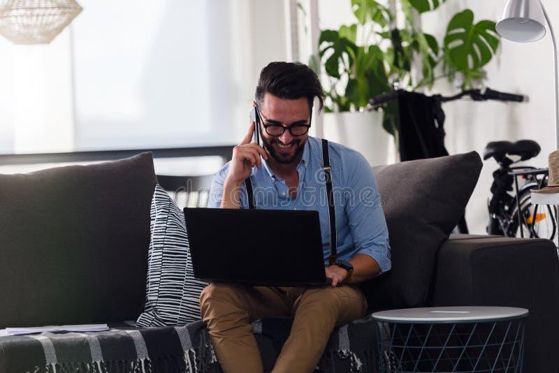 Happy Smiling Man Using Smartphone Working on Laptop Computer while ...