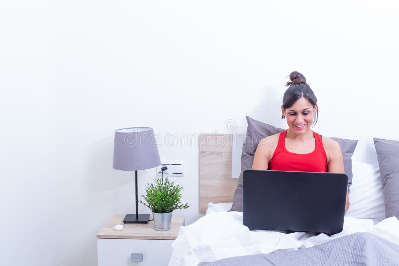 Happy Smiling Young Woman, Relaxing in Her Bed with Laptop Computer ...