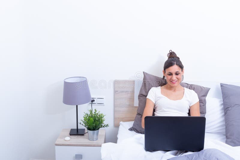 Happy Smiling Young Woman, Relaxing in Her Bed with Laptop Computer ...