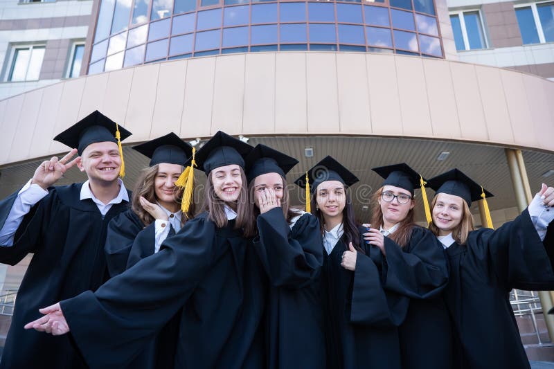 Happy Students in Graduate Gown Stand in a Row Against the Backdrop of ...