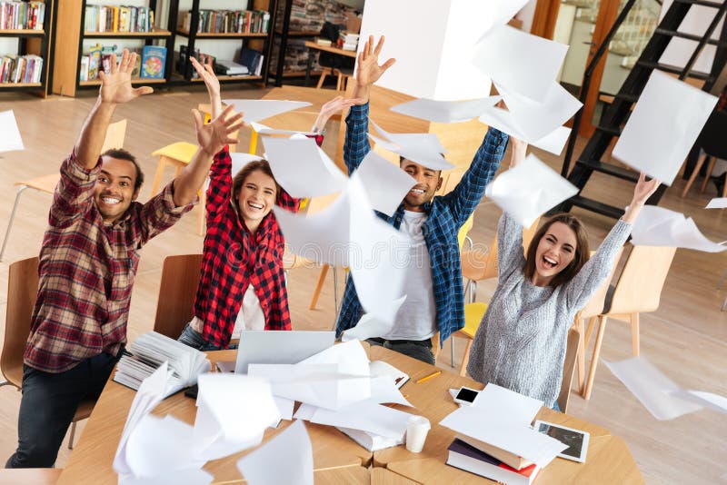 Happy Students Sitting in Library Throw Up the Paper. Stock Photo ...