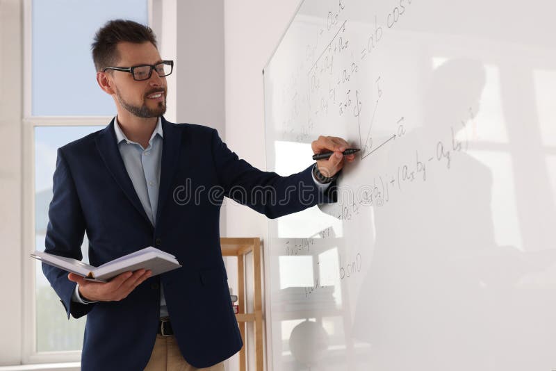 Happy Teacher with Book Explaining Mathematics at Whiteboard in ...