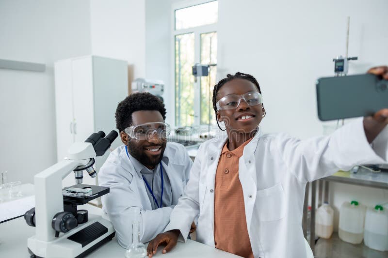Happy Teacher and Student in Lab Coats Making Selfie on a Phone Stock ...