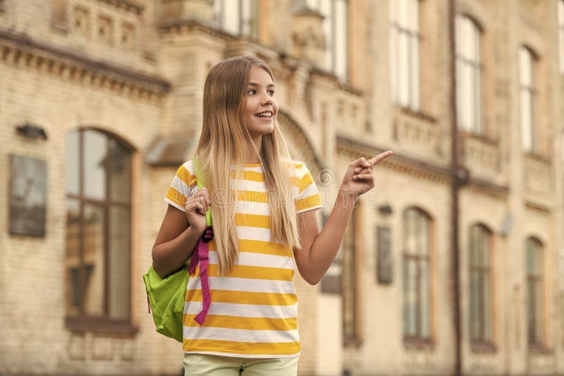Happy Teen Girl With School Backpack Pointing Finger Looking Aside