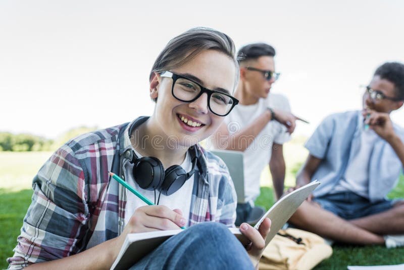 Happy Teenage Boy Taking Notes and Smiling at Camera while Studying ...