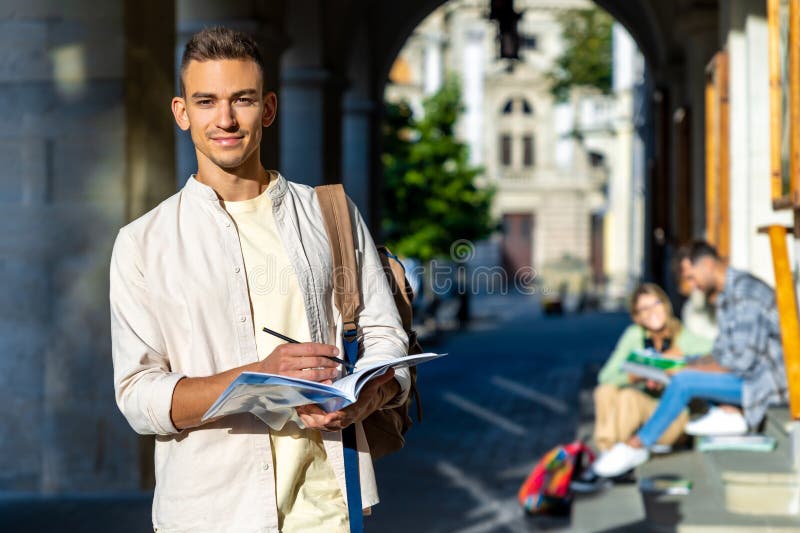 Happy University Male Student Standing at Campus with Book Stock Photo ...