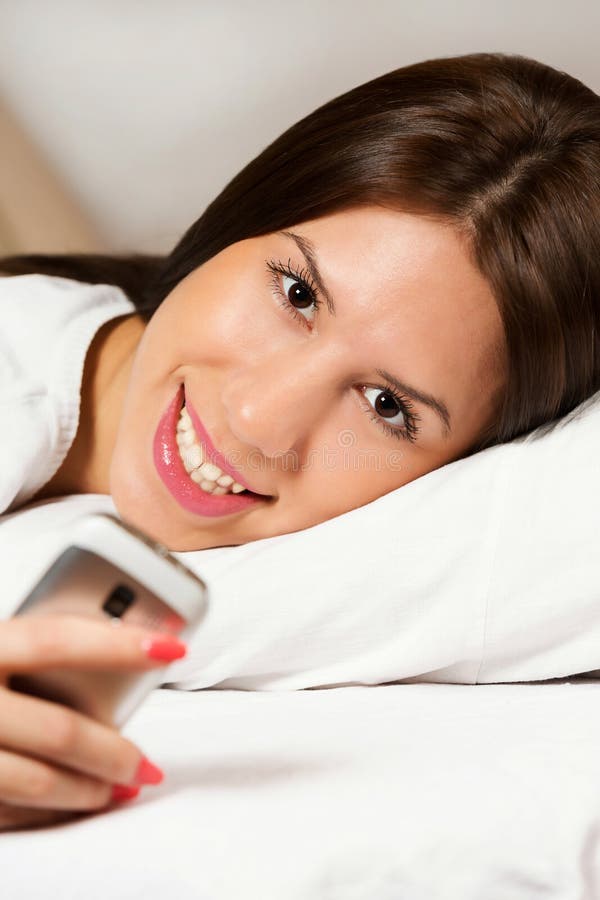 Happy Woman Lying on Bed Smiling, Reading a Text Message Stock Photo ...