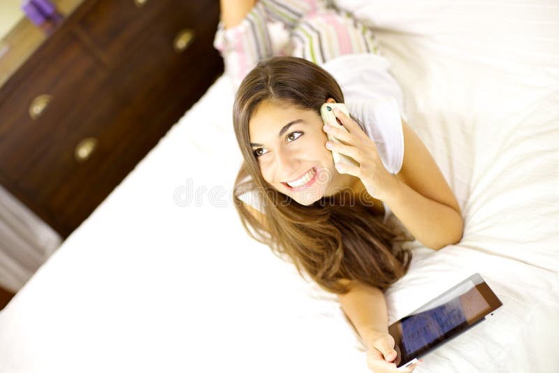 Happy Woman on the Phone Lying in Bed with Tablet Stock Image - Image ...