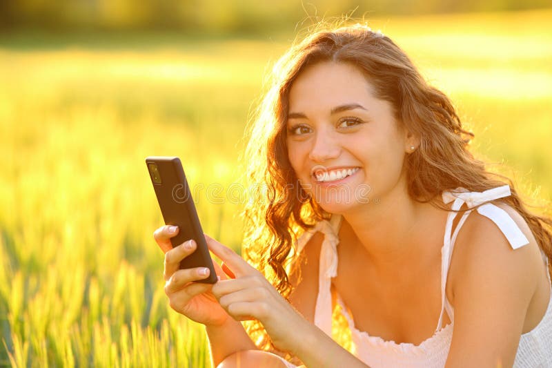 Happy Woman Posing in a Field Holding Phone Stock Image - Image of ...