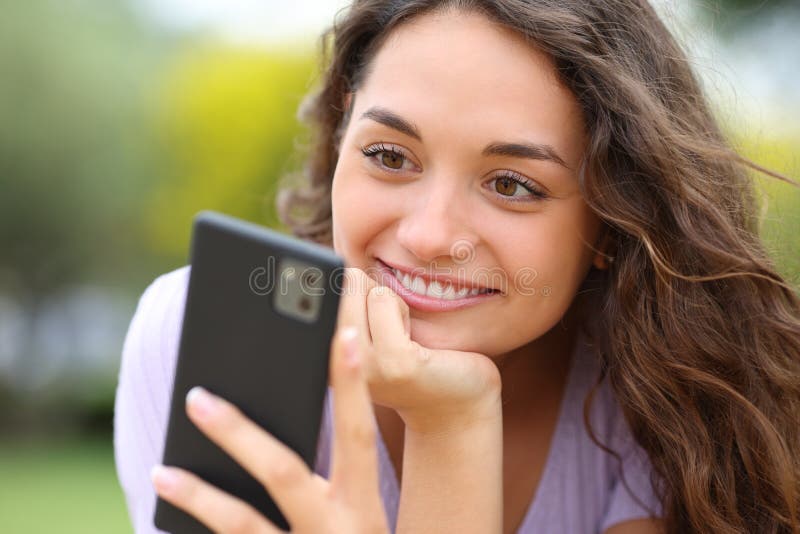 Happy Woman Reading Message on Phone in a Park Stock Image - Image of ...