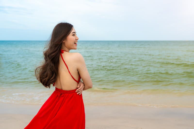 Happy Woman In Red Dress Standing With Arms Crossed On Sea Beach Stock