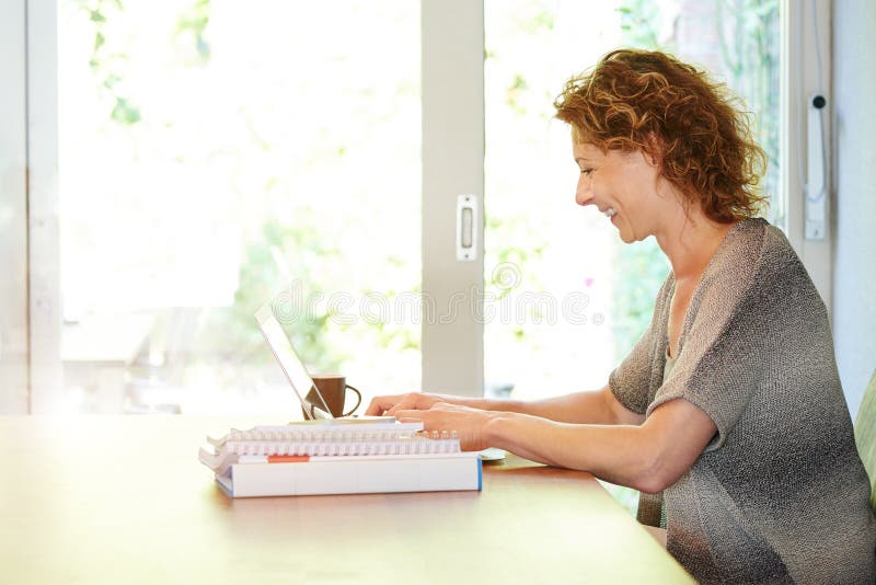 Happy Woman Sitting at Table Working on Laptop Stock Image - Image of ...