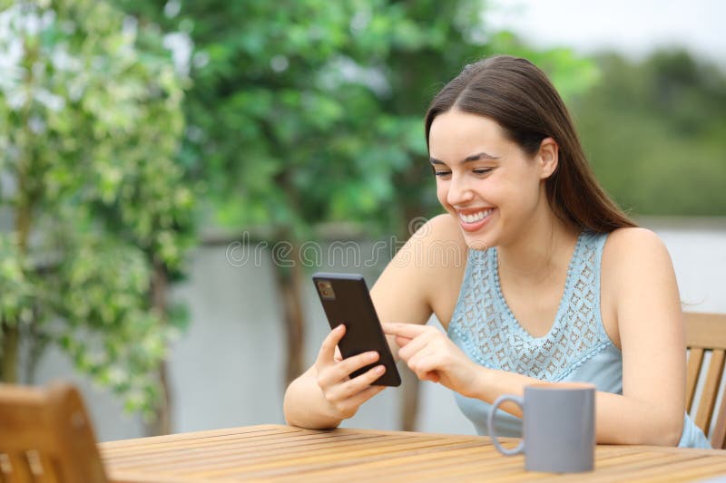 Happy Woman in a Terrace Browsing Mobile Phone Content Stock Image ...