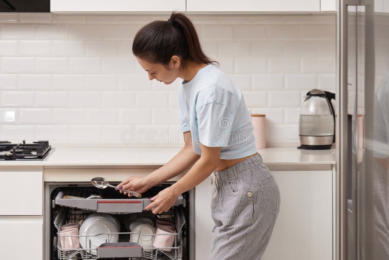 Pretty Woman Unloading from Open Dishwasher Machine with Clean Utensils ...