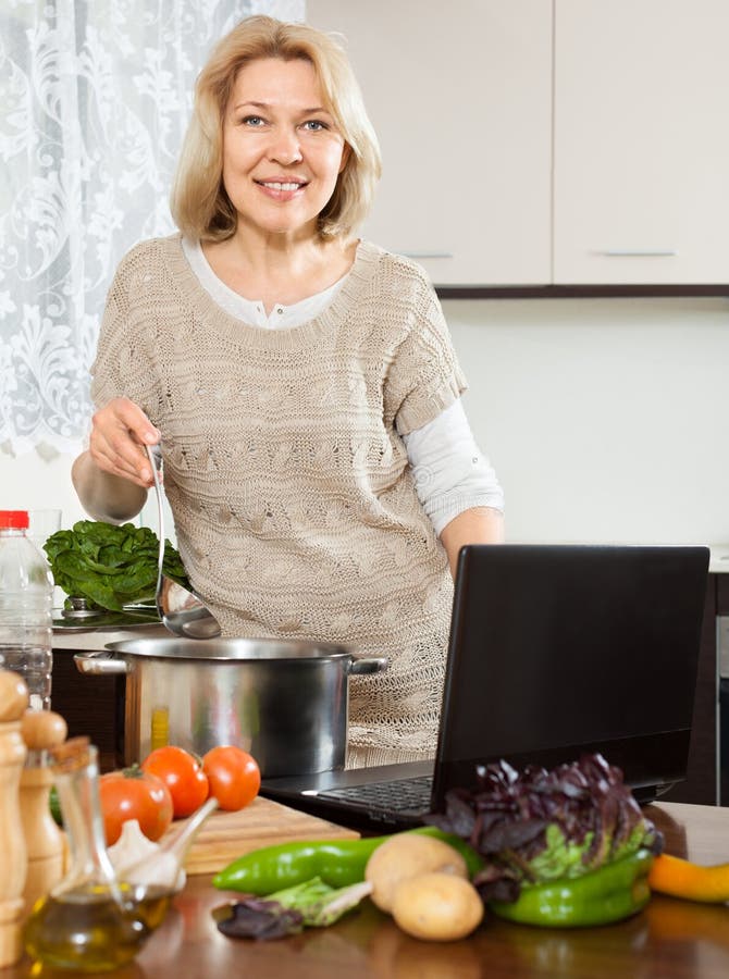Happy Woman Using Notebook while Cooking Soup Stock Photo - Image of ...