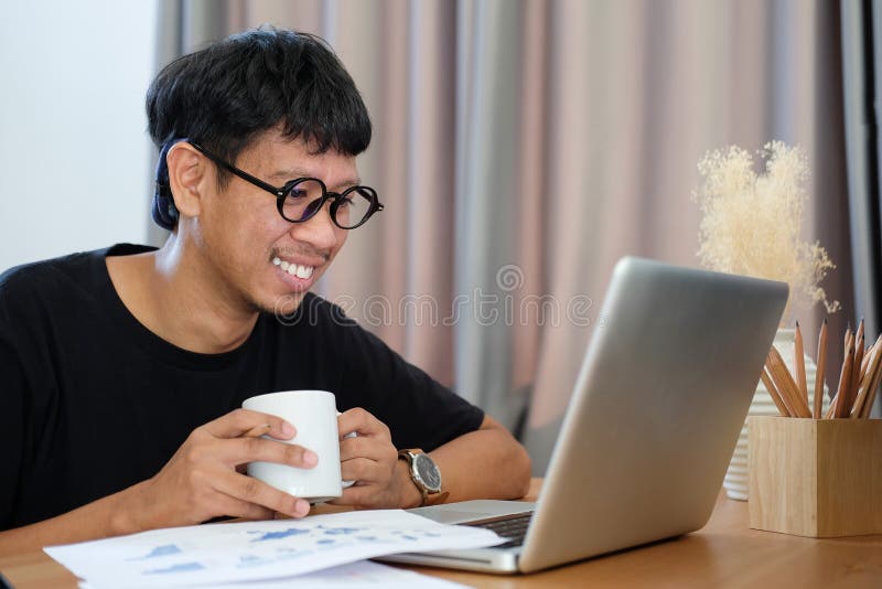 Happy Young Asian Man Holding Coffee Cup and Using Computer Laptop ...