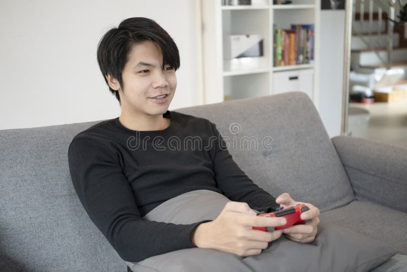 Young Asian Man Playing Video Game with Joystick on Sofa. Stock Image ...