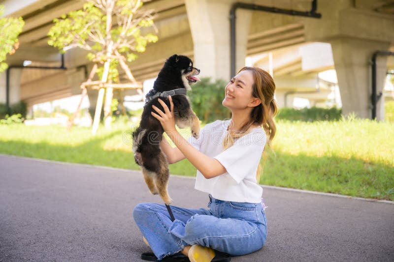 Happy Young Asian Woman Playing and Sitting on Road in the Park with ... Happy Young Asian Woman Playing and Sitting on Road in the Park with ...