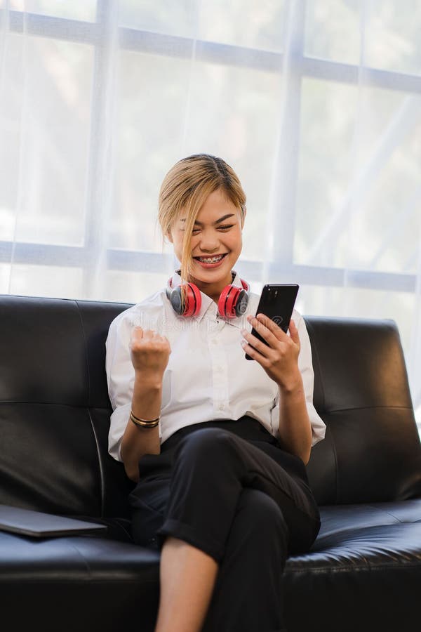 Happy Young Asian Woman Relaxing on Comfortable Sofa at Home Texting on ... Happy Young Asian Woman Relaxing on Comfortable Sofa at Home Texting on ...