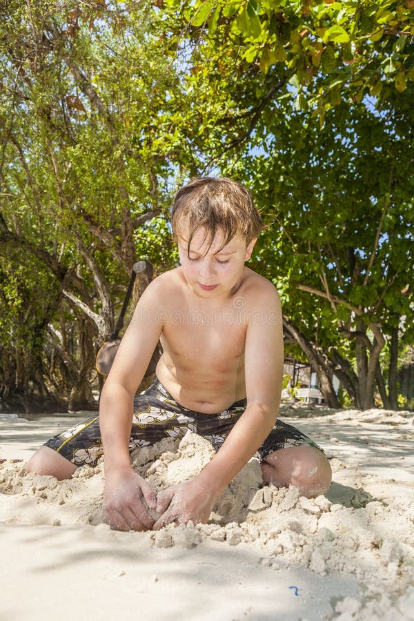 Happy Young Boy is Digging in the Sand of the Beach Stock Photo - Image ...