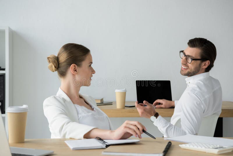 Young Business Colleagues Smiling Each Other while Working Together ... Young Business Colleagues Smiling Each Other while Working Together ...