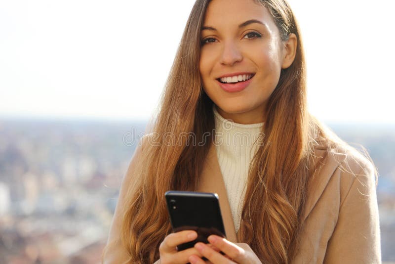Happy Young Business Woman Using a Smartphone and Looking at Camera ...