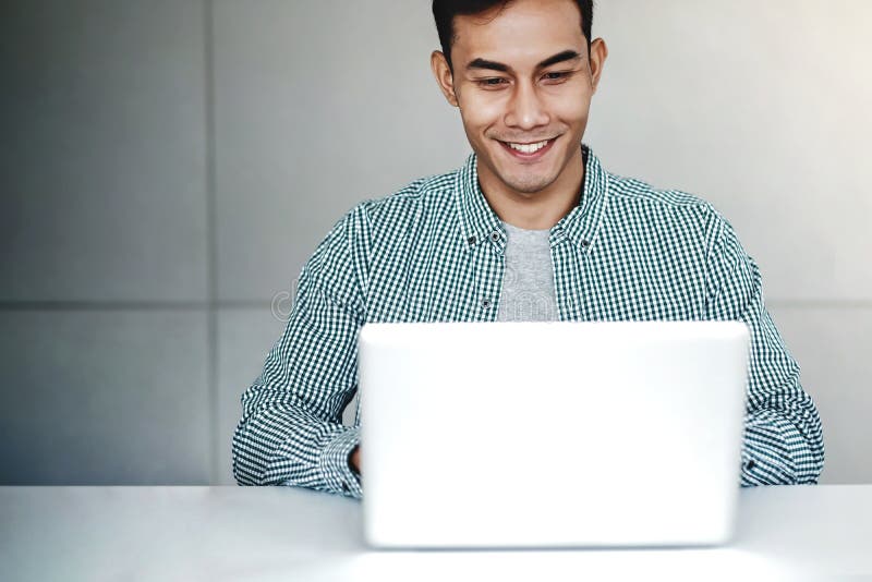 Happy Young Businessman Working on Computer Laptop in Office. Smiling ... Happy Young Businessman Working on Computer Laptop in Office. Smiling ...