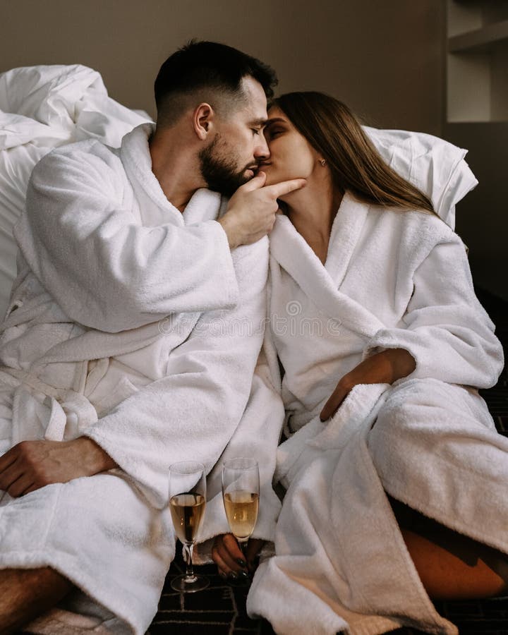 Happy Young Couple Hugging And Kissing Sitting On Floor Near The Bed In