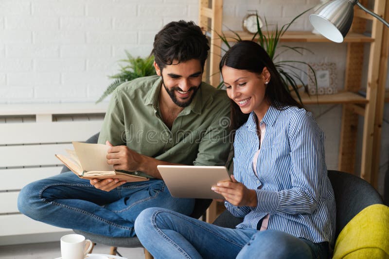 Happy Young Couple Relaxing. Reading Something on Book and Tablet ...