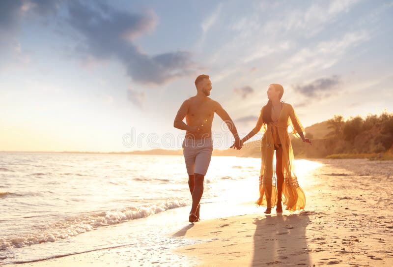 Happy Young Couple Running Together on Beach at Sunset Stock Photo ...