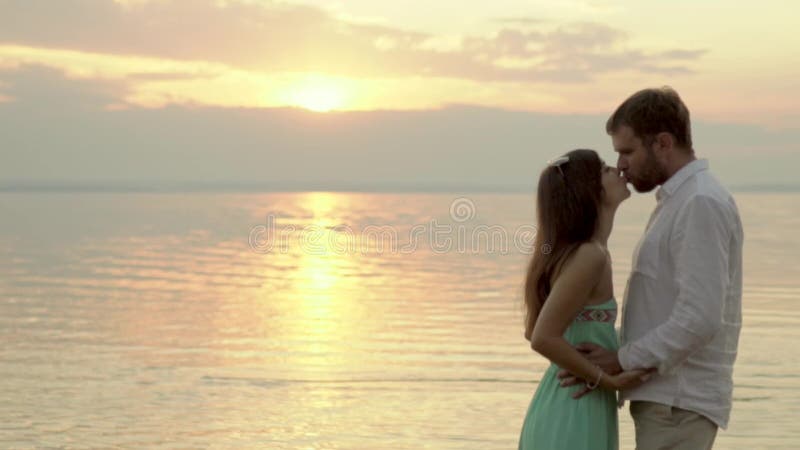 Happy Young Couple Stand On The Beach On Sunset Girlfriend Kiss Her
