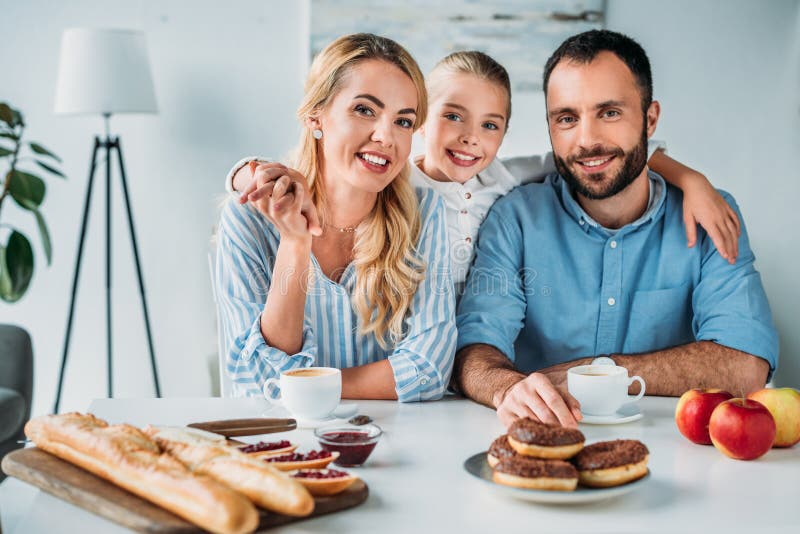 Happy Young Family with Breakfast on Table Looking Stock Photo - Image ...