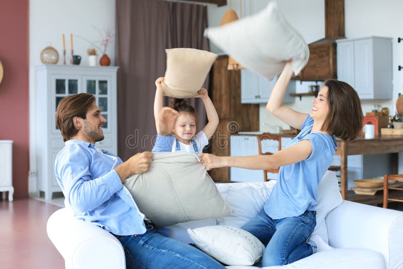 Happy Young Family Having Fun with Pillows on Sofa Stock Photo - Image ...