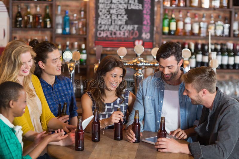 Happy Young Friends with Beer Bottles Standing Around Table Stock Image ...